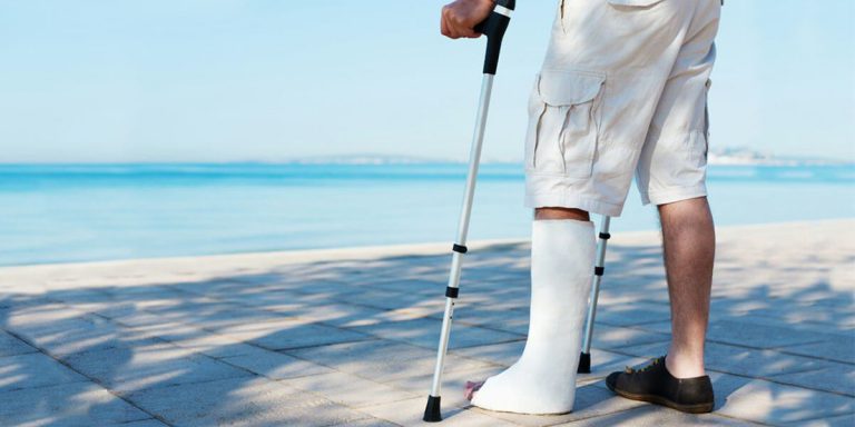man_in_crutches_at_the_beach - Women Daily Magazine